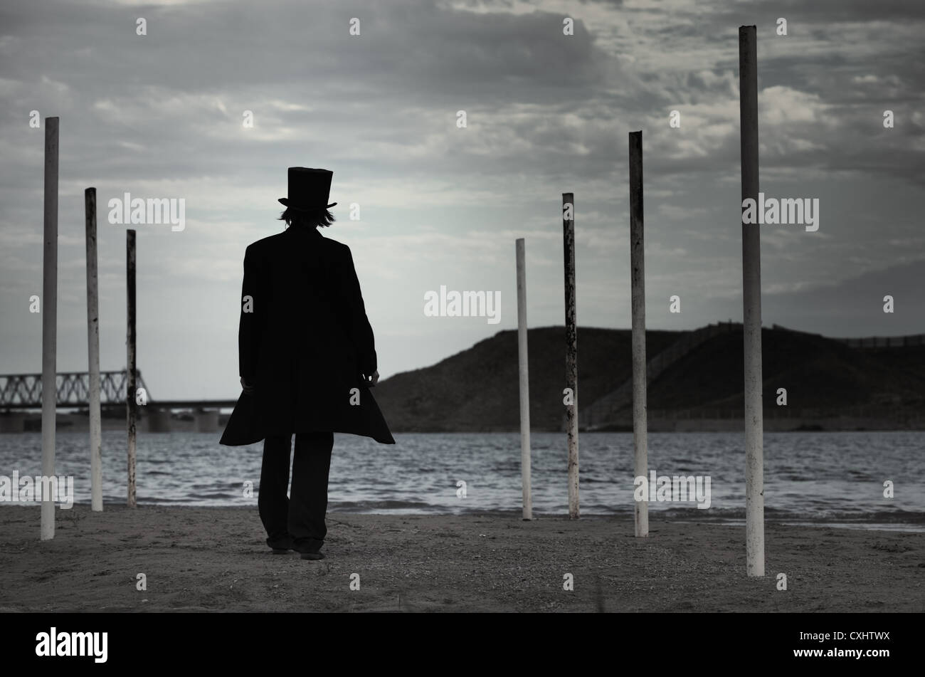 Rear view on alone man in the black coat and top-hat going to the sea ...