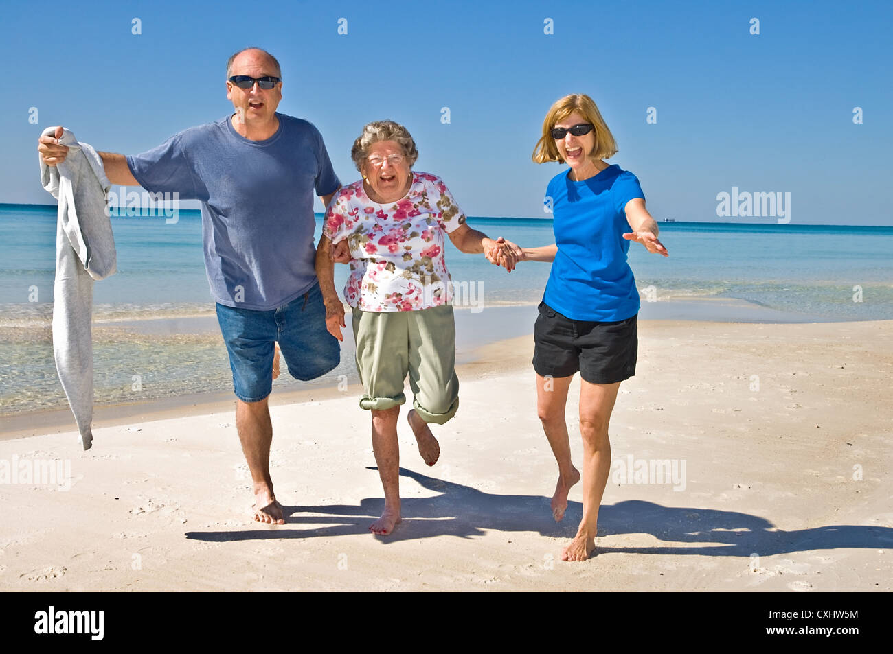 Three adults having fun on a beach, one elderly and two middle aged ...