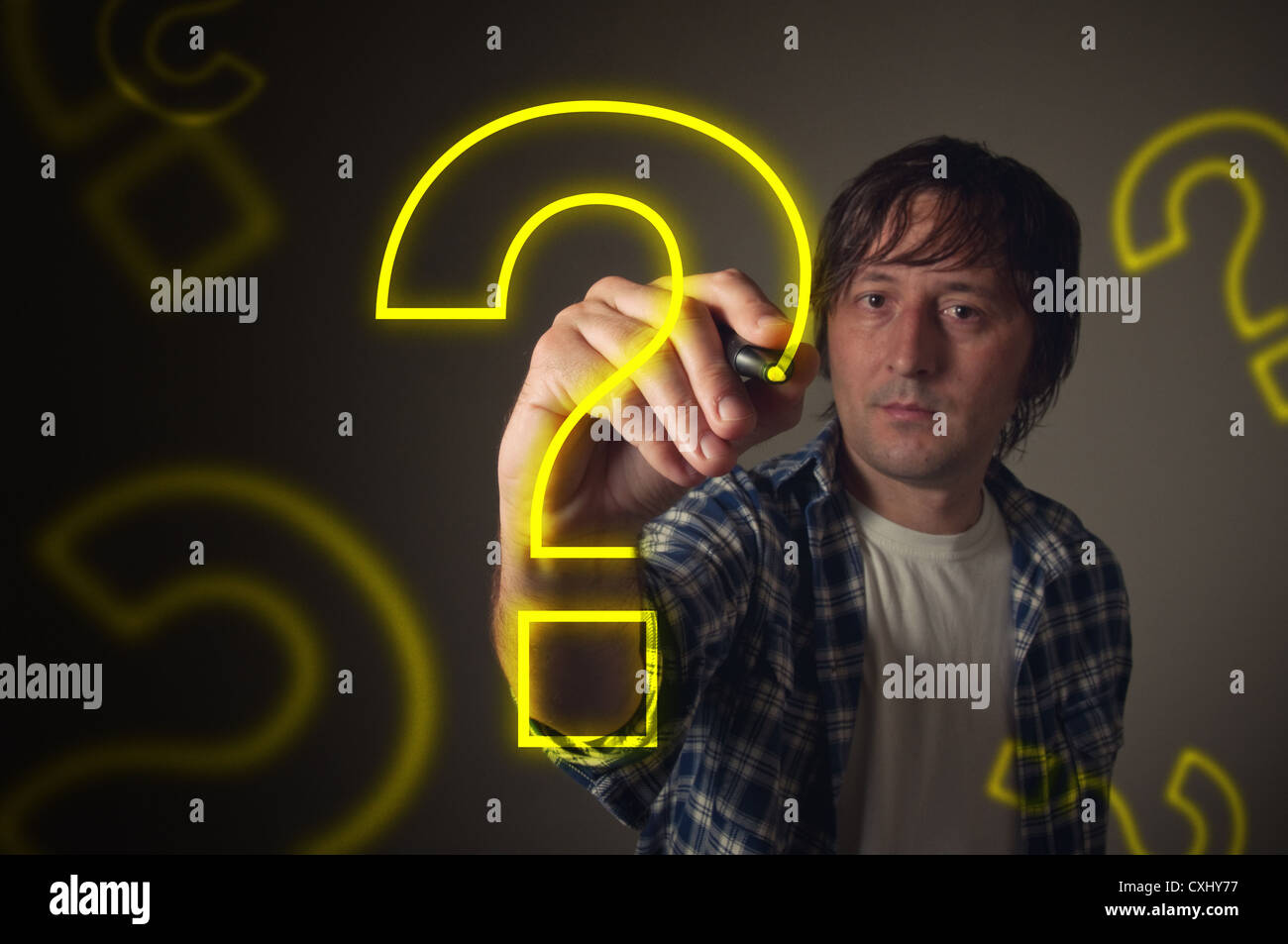 Young adult casual designer drawing question marks with yellow pen ...