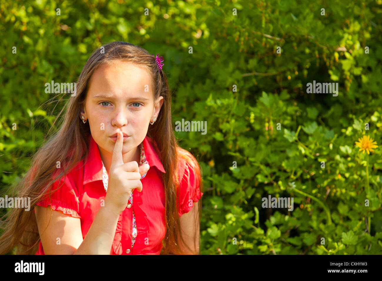 Beautiful young girl with her finger over her mouth, hushing Stock ...