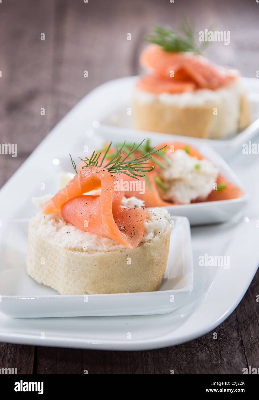 Salmon starters on small plates against wooden background Stock Photo ...