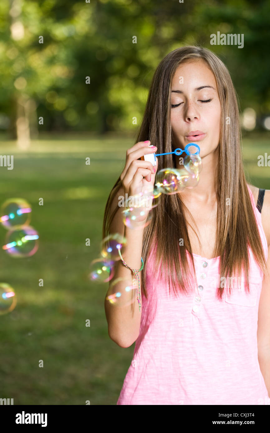 Portrait Of A Beautiful Young Girl Blowing Soap Bubbles Outdoors In The