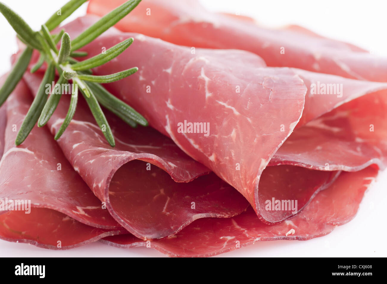 Pressed meat slices rolled as closeup on a white plate Stock Photo - Alamy