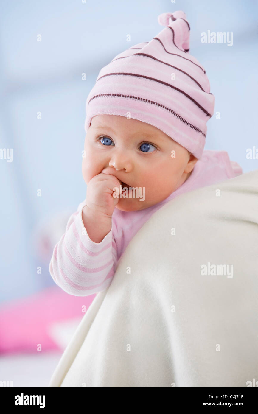 Baby girl in woolly hat with finger in mouth, close up Stock Photo - Alamy