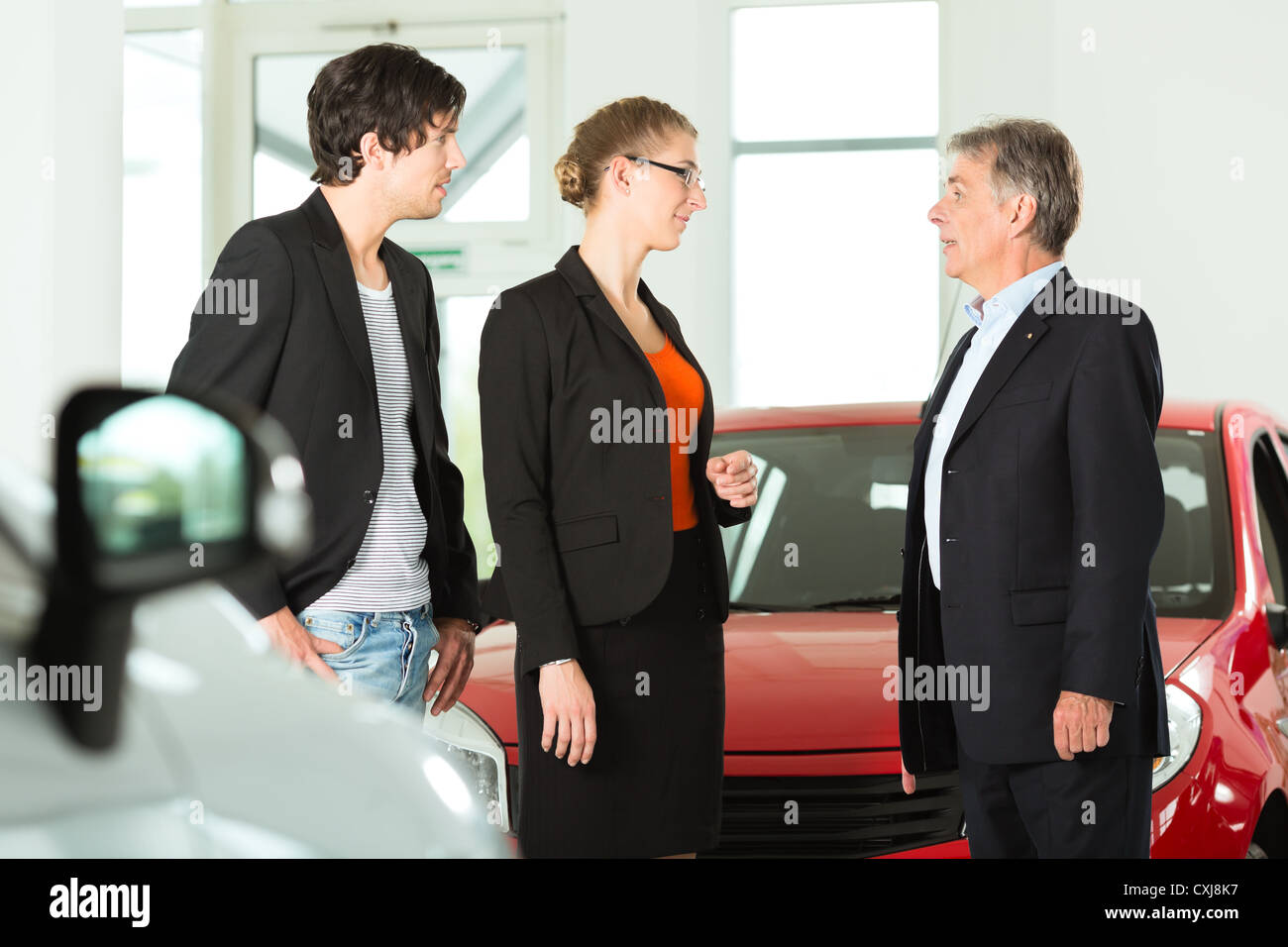 Mature single man with autos in light car dealership with a young ...