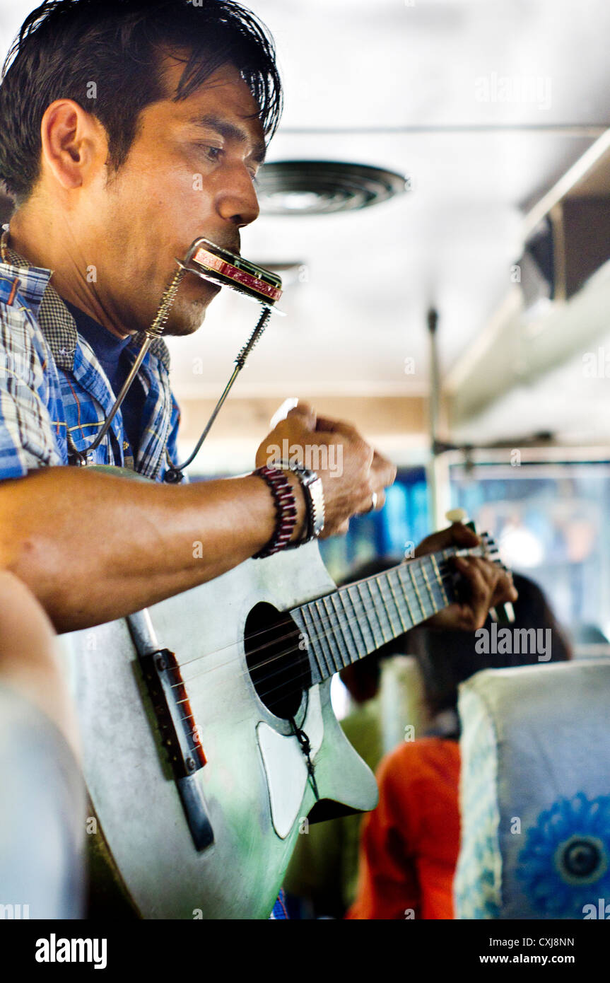 An indonesian man busking by singing in the bus, asia scene. Slight ...
