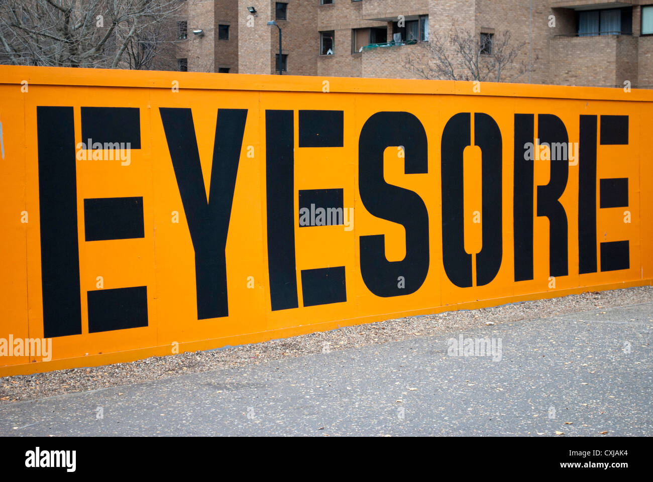 Black and yellow 'EYESORE' sign on barrier around construction site ...