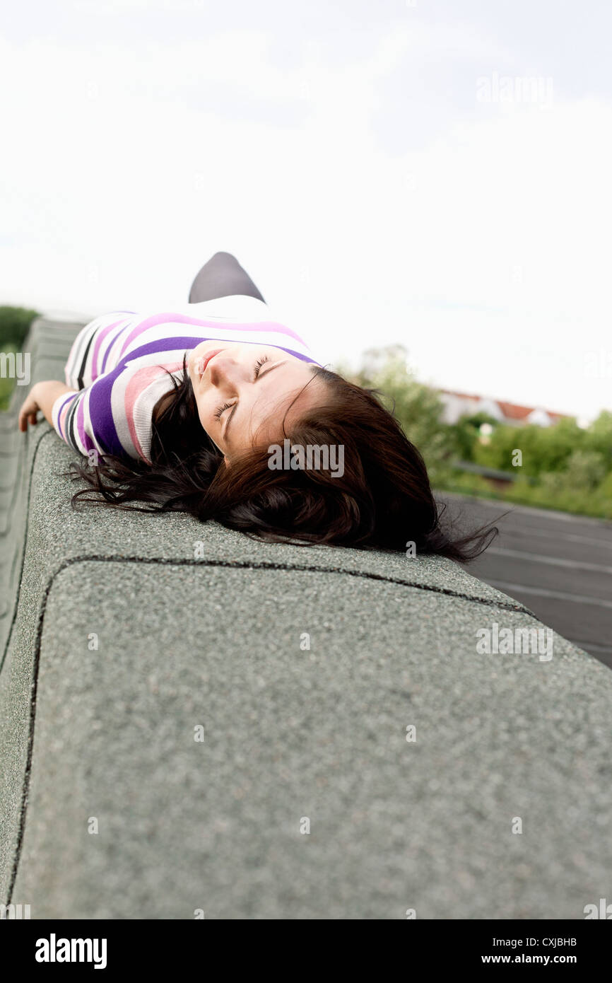 Germany, Hamburg, Young woman lying on wall Stock Photo - Alamy