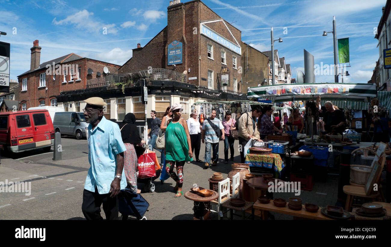 People walking past market stalls on Walthamstow High Street on a sunny ...