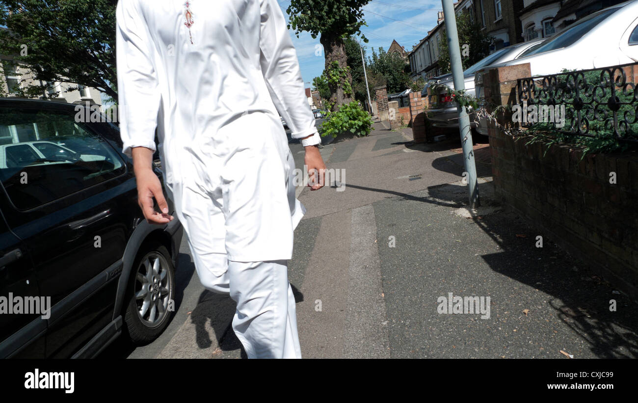 A Muslim man walking down a street in Walthamstow East London England ...