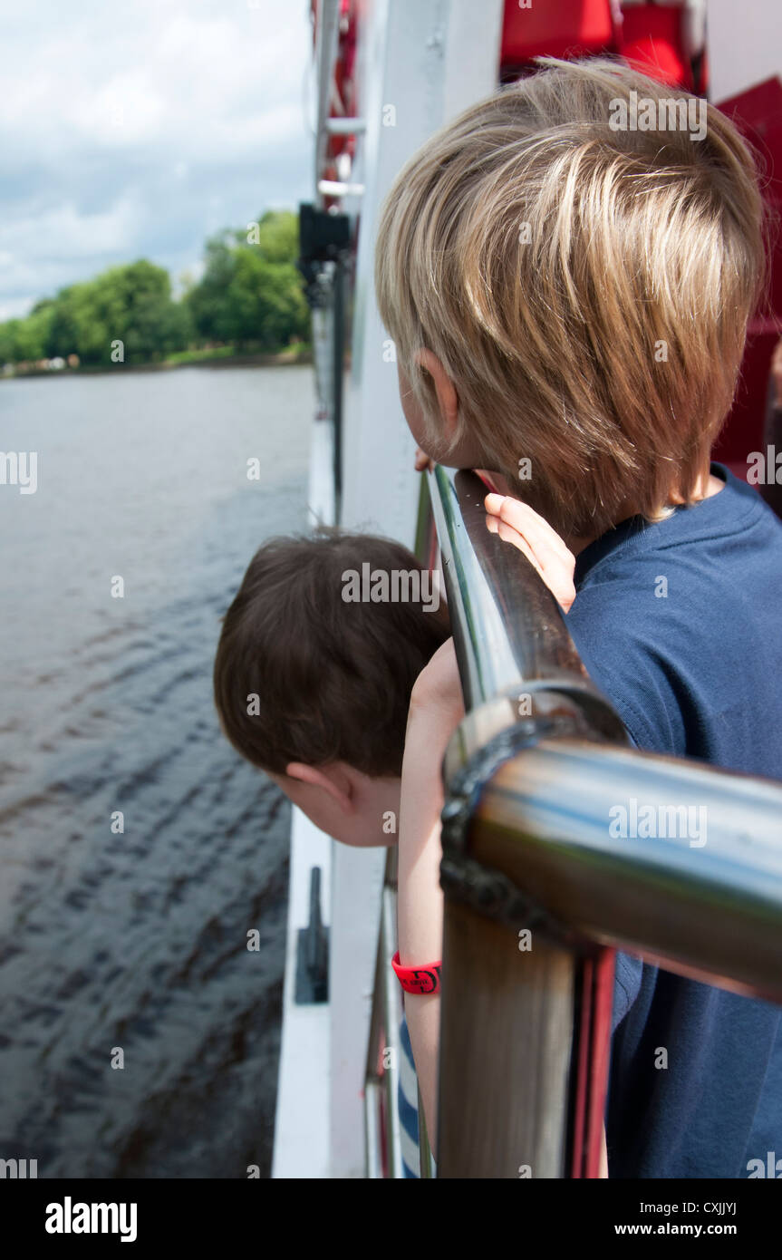 Two boys leaning over boat railings to look up the river Ouse Stock ...