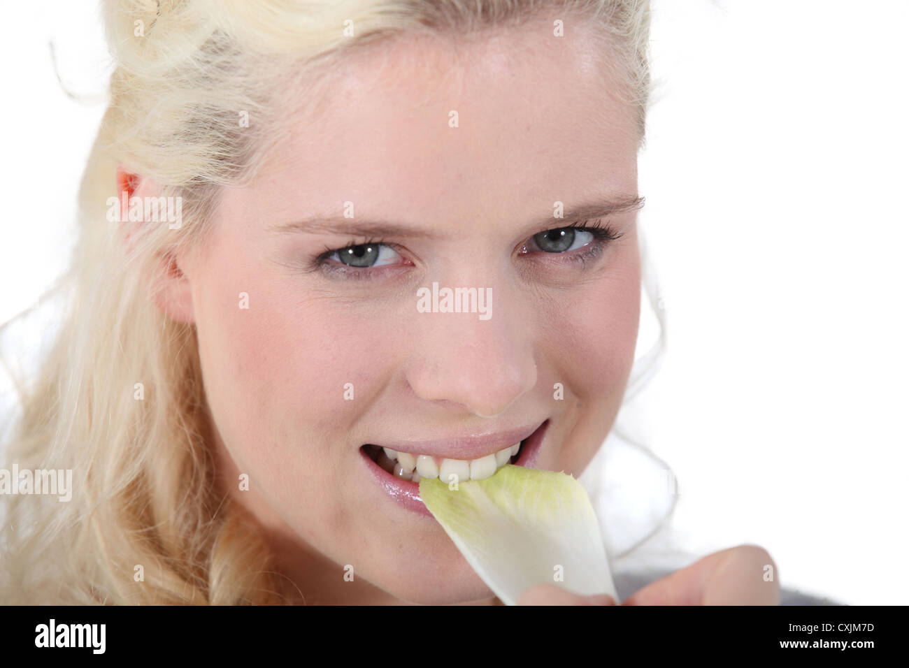 dynamic blonde woman crunching a leaf of endive Stock Photo - Alamy