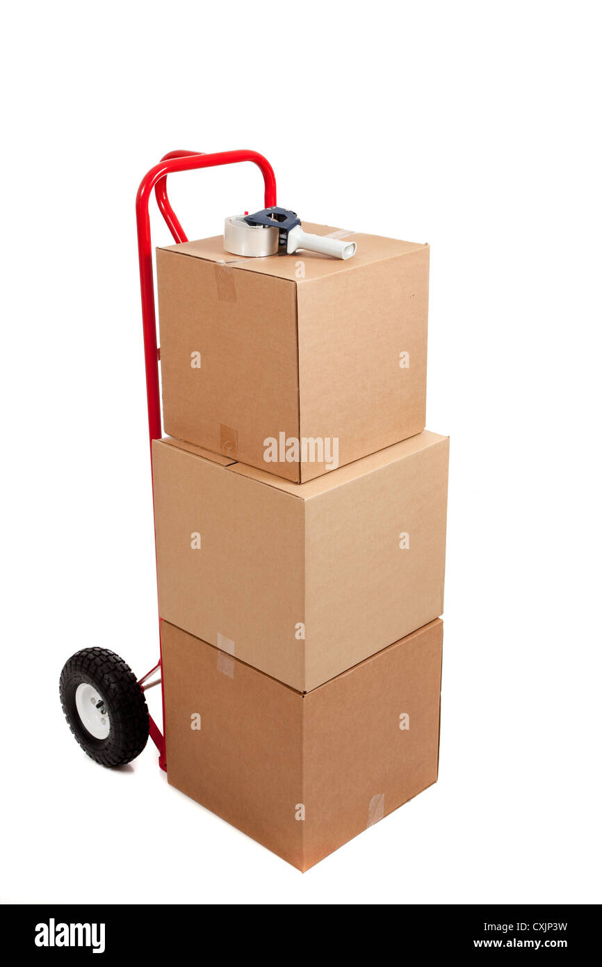 Stack of brown packing boxes and a tape gun on a red hand truck on a ...