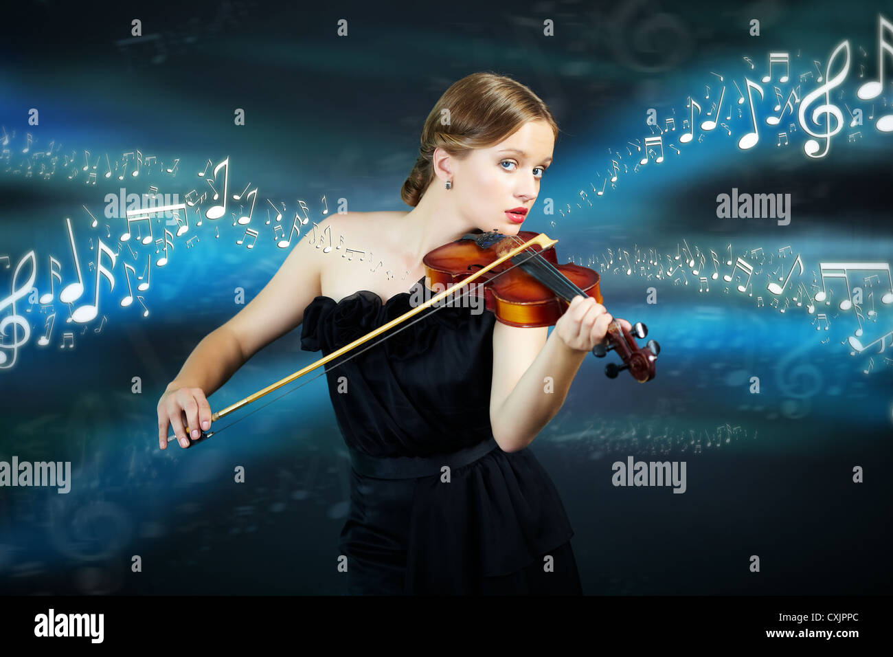 Portrait of a young female playing the violin and looking at camera ...
