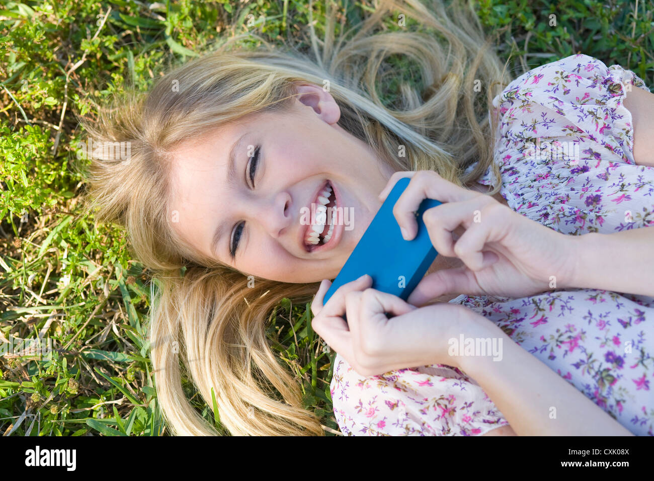 Close-up Portrait of Woman Lying on Grass holding Cell Phone Stock ...