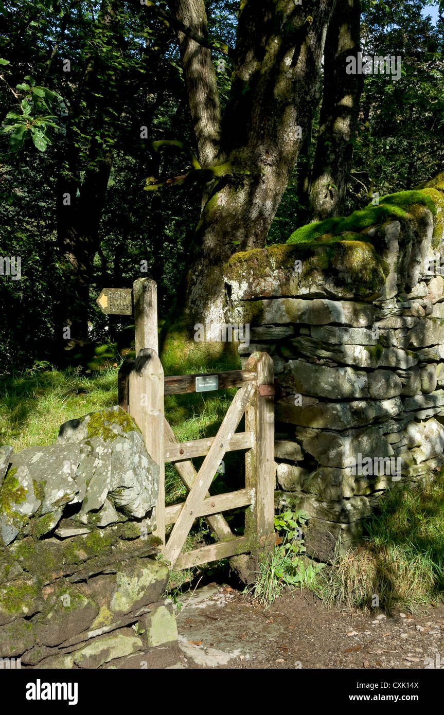 Public footpath path with wooden gate set in dry stone wall in summer ...