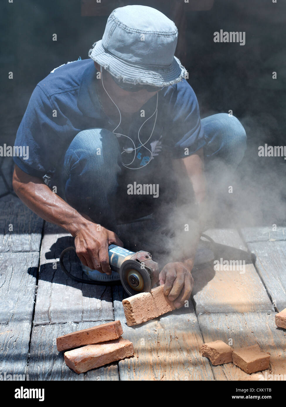 Angle grinder. Builder using a hand powered angle grinder to cut bricks ...