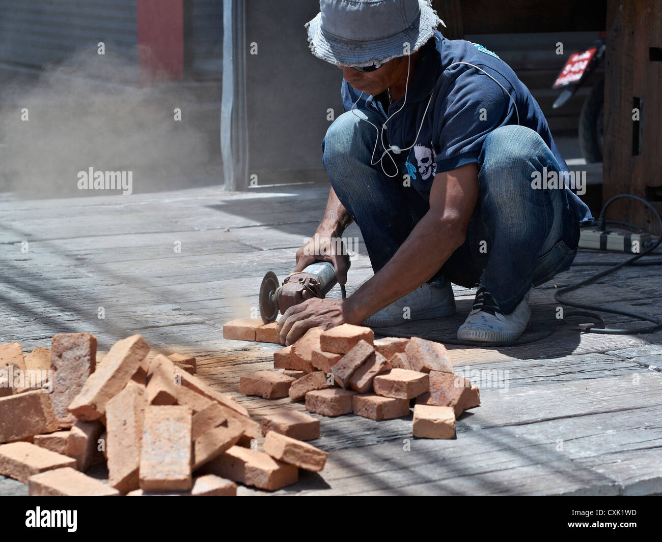Angle grinder. Builder using a hand powered angle grinder to cut bricks ...