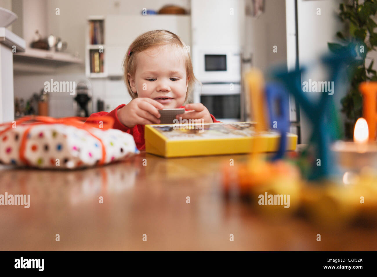 Little Girl Sitting at Table Opening Gifts Stock Photo - Alamy