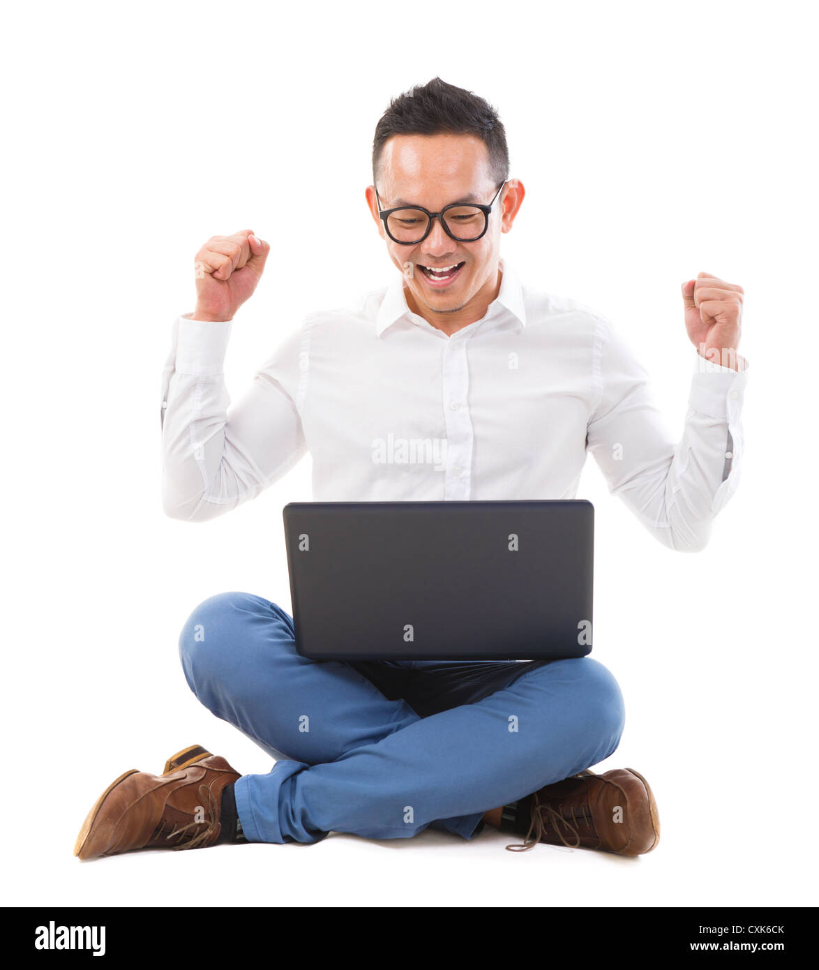 Excited Asian man using laptop on the floor over white background Stock ...