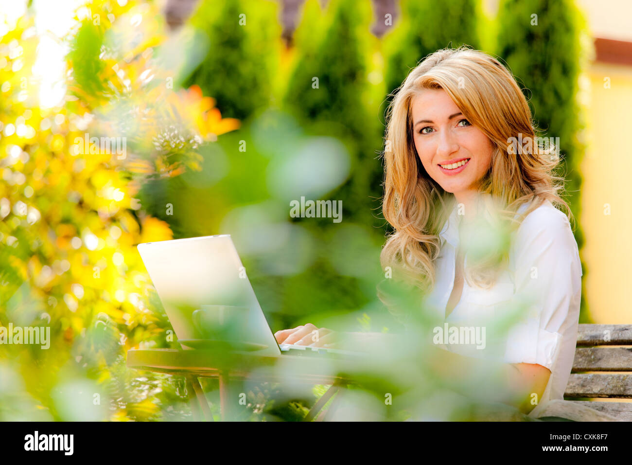 Woman with laptop in garden Stock Photo - Alamy