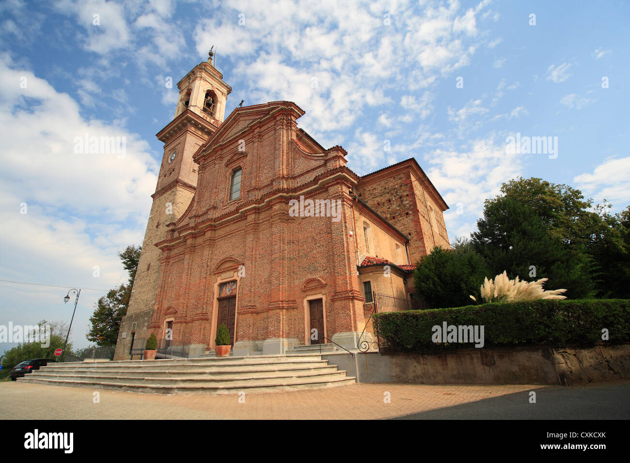 Typical Italian church and bell tower of pink stone against a blue sky ...