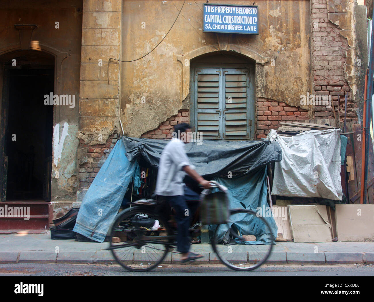 Cyclist rides past improvised shop in a poor district of Kolkata ...