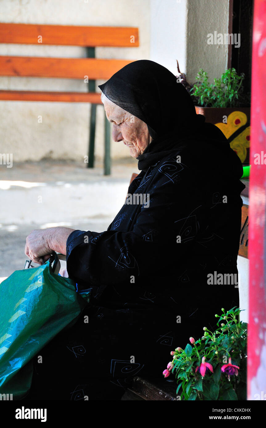 Elderly Greek woman dressed in black sitting waiting for a bus in the ...