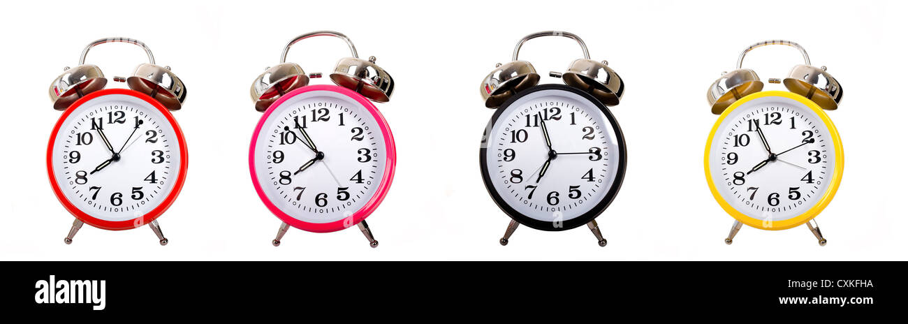 Several brightly colored traditional alarm clocks thrown on a white ...