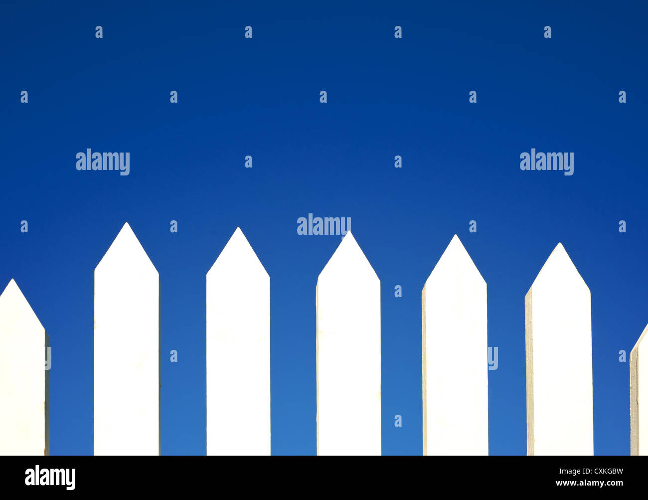 A white picket fence background in front of a bright blue sky with copy ...