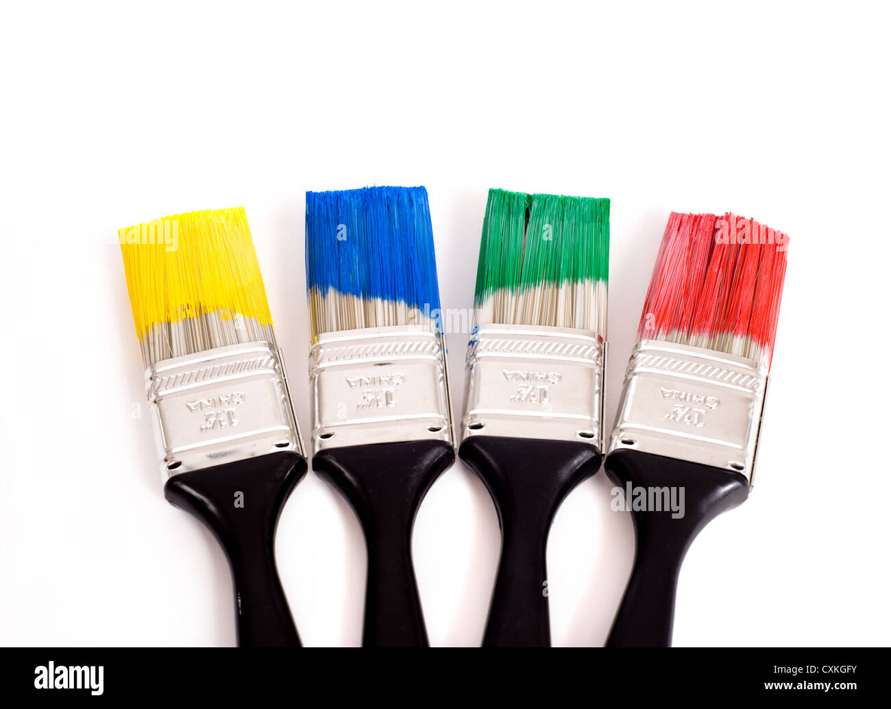 A row of primary colored paint brushes on white background with copy ...