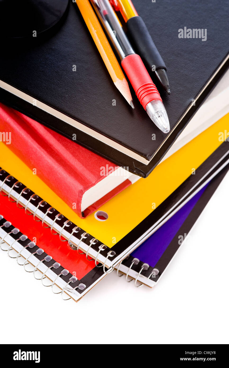 A stack of school books and spiral notebooks with a pencil and pens on ...