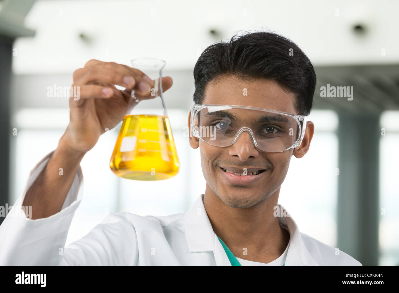Indian male scientific researcher looking at a flask of liquid Stock ...