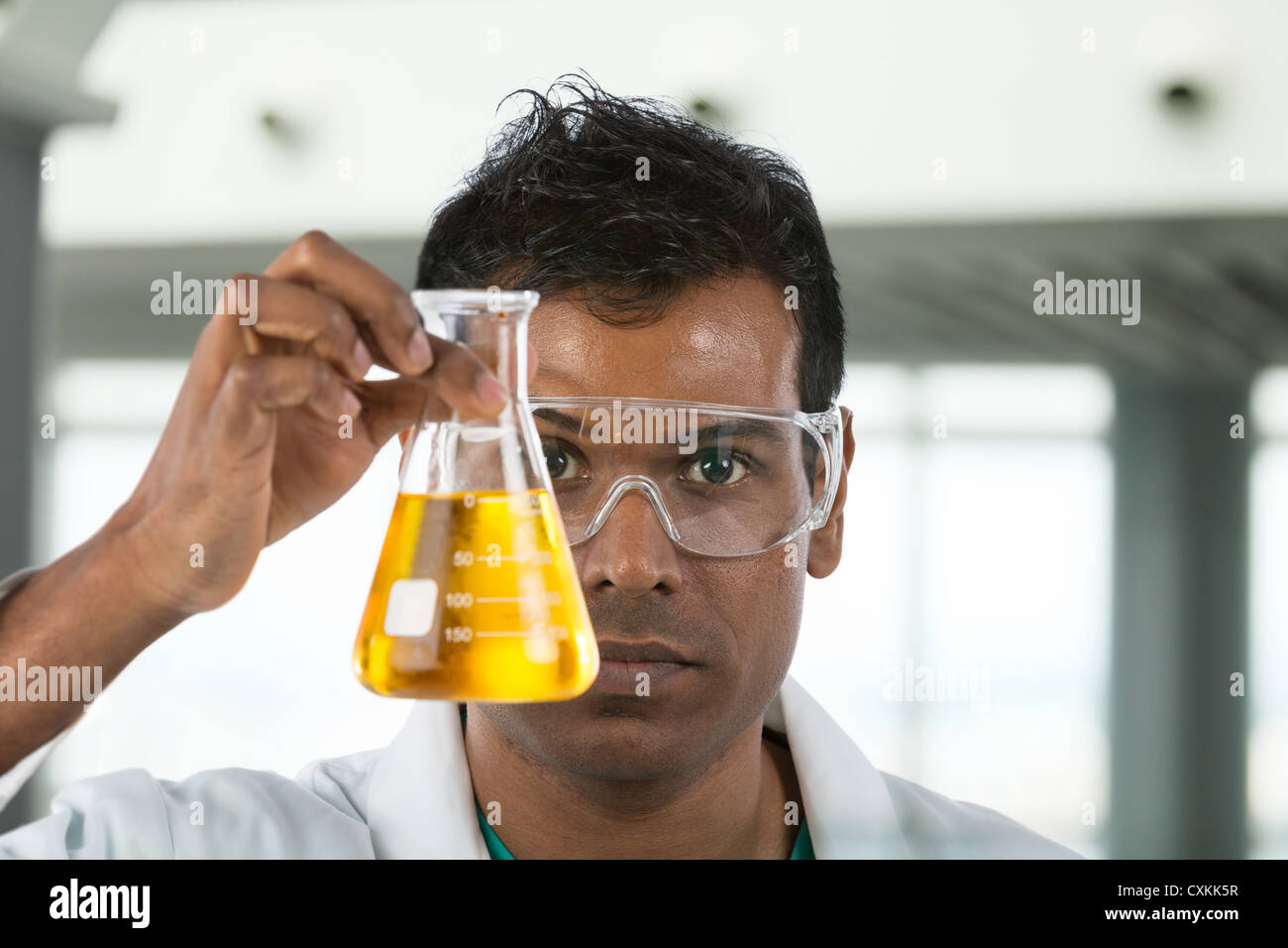 Indian lab technician holding a flask Stock Photo - Alamy