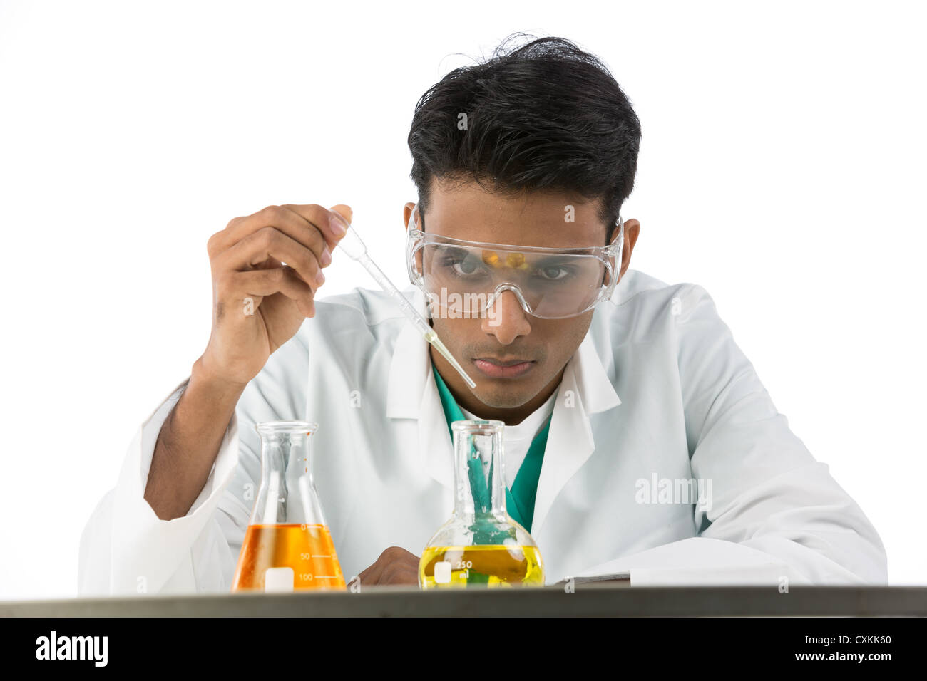 Indian male scientific researcher looking at a flask of liquid Stock ...
