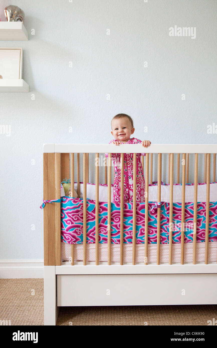 Baby girl standing in crib Stock Photo - Alamy