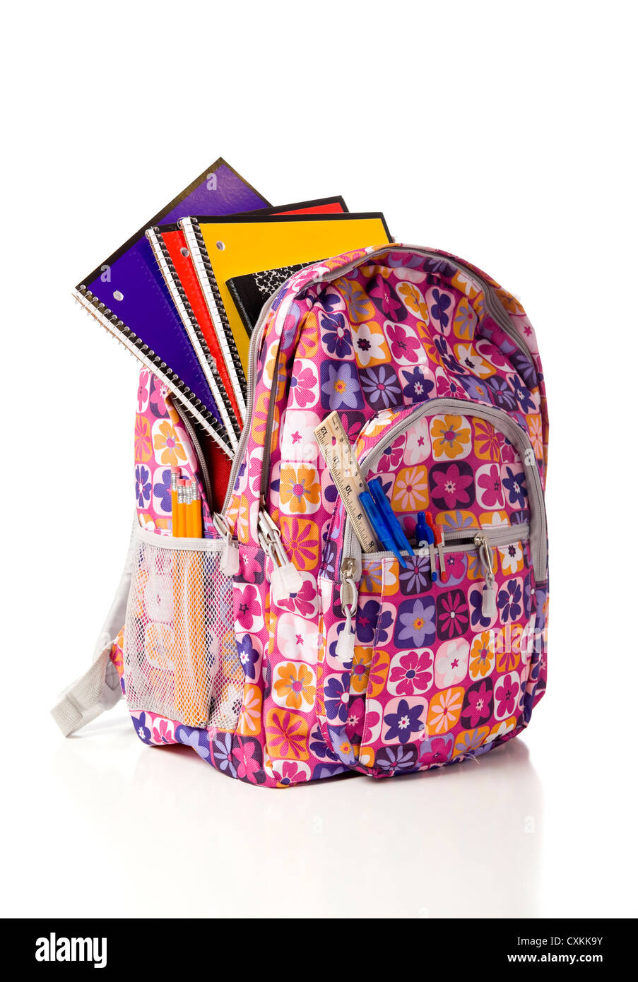 A pink school backpack overflowing with school supplies on a white ...