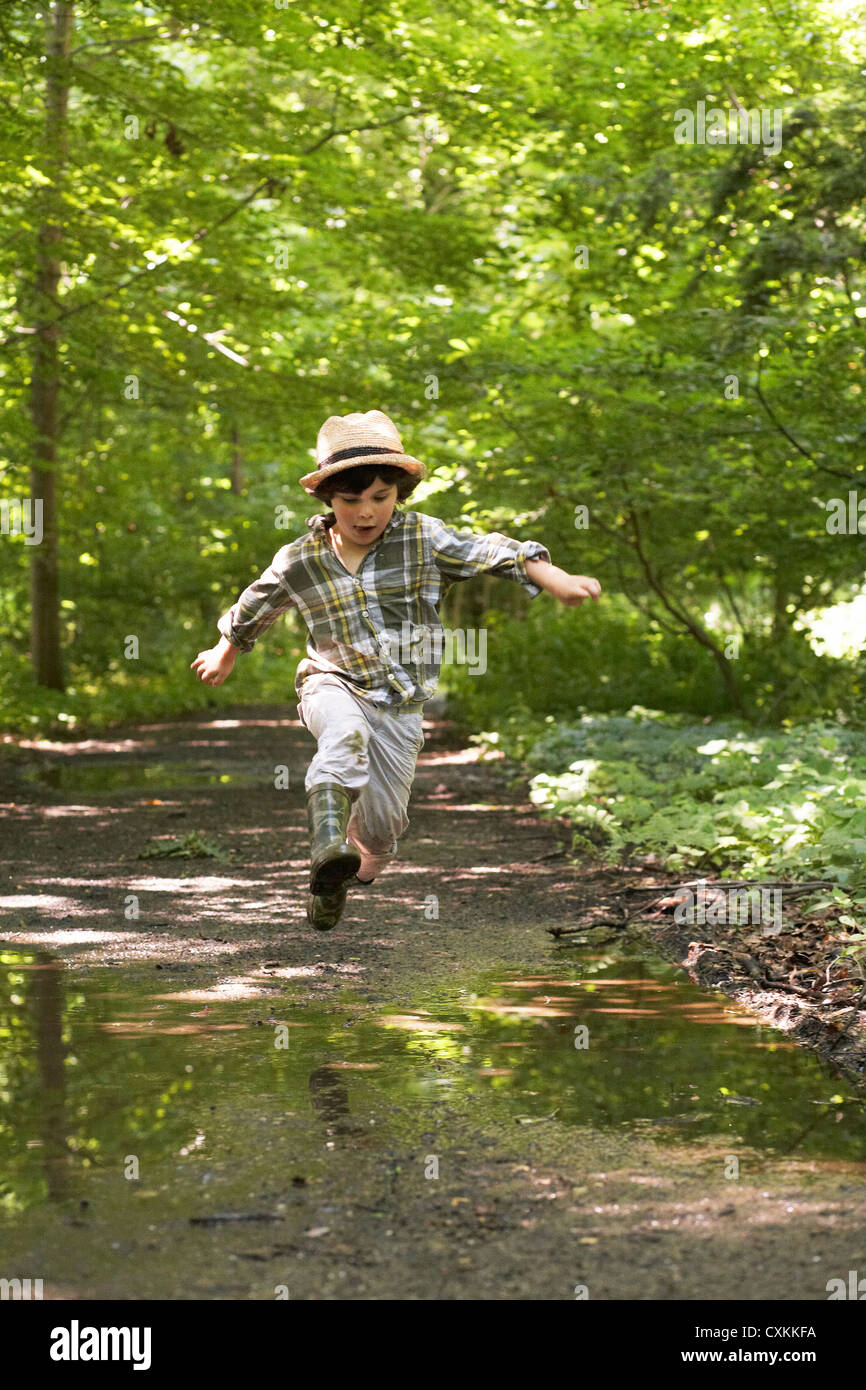 Young boy jumping over puddles Stock Photo - Alamy