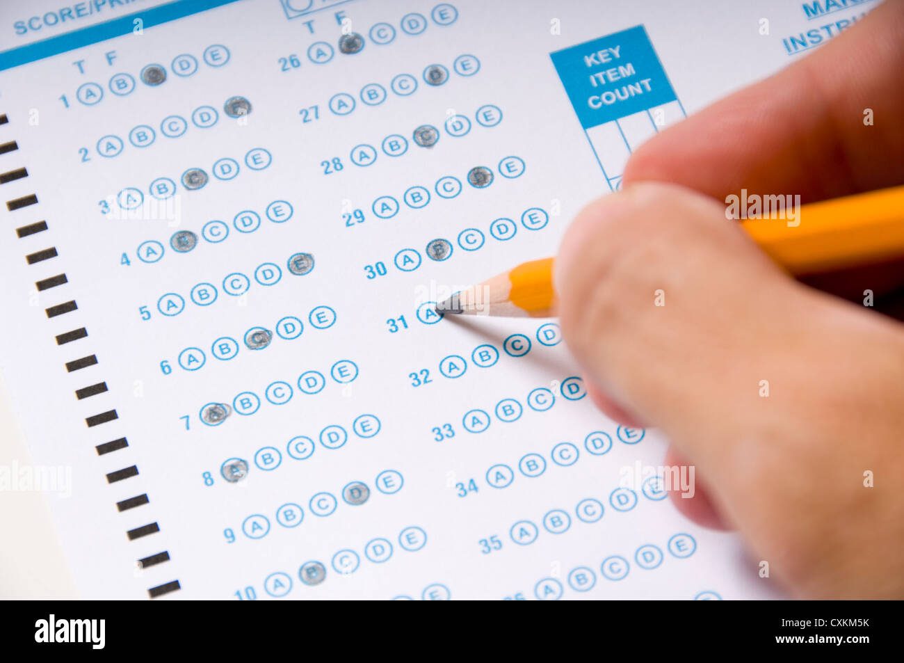 A hand holding a yellow pencil filling in a computer checked answer ...