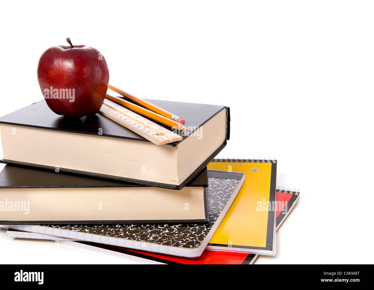 A stack of school books and spiral notebooks with a pencil and a ruler ...