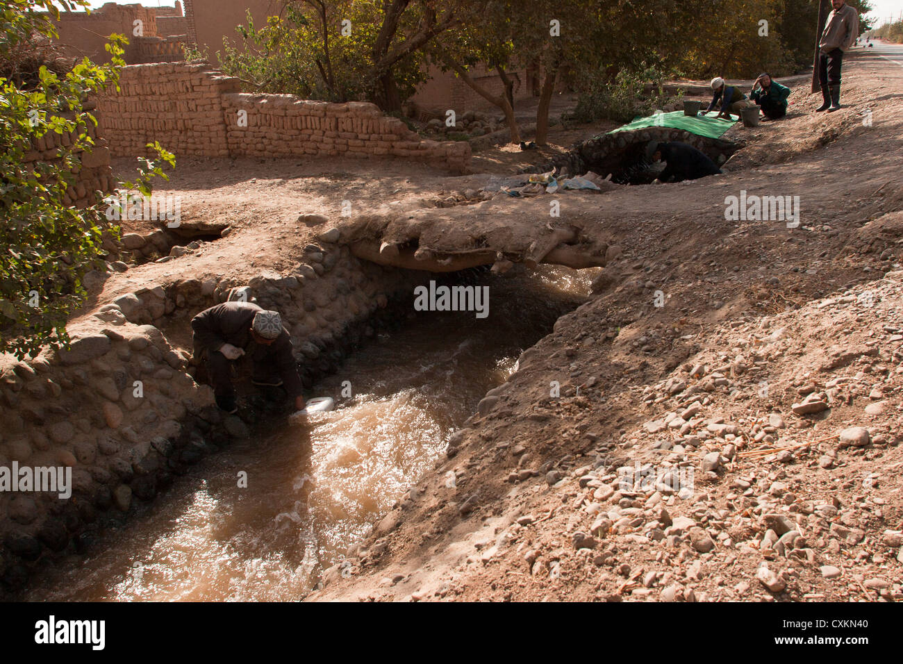 A Uighur man collects water from a stream fed by the karez water system ...