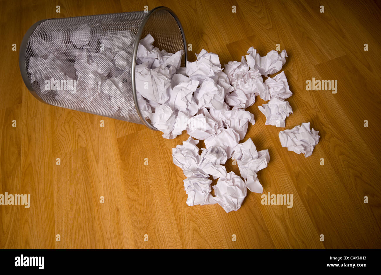 A spilling office trash can on a wood floor with copy space Stock Photo ...