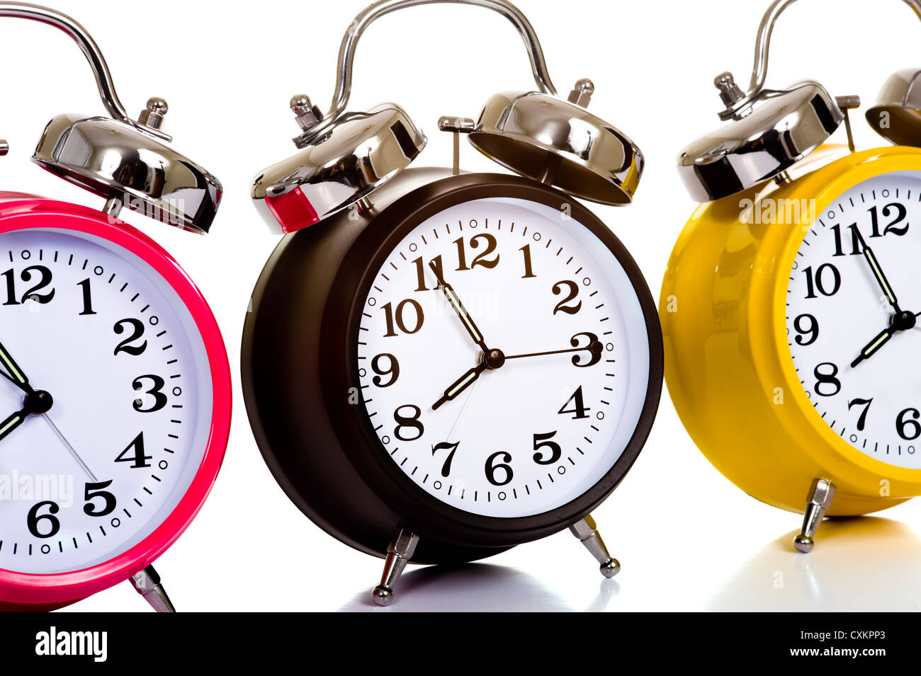 A group of colorful, traditional alarm clocks on a white background ...