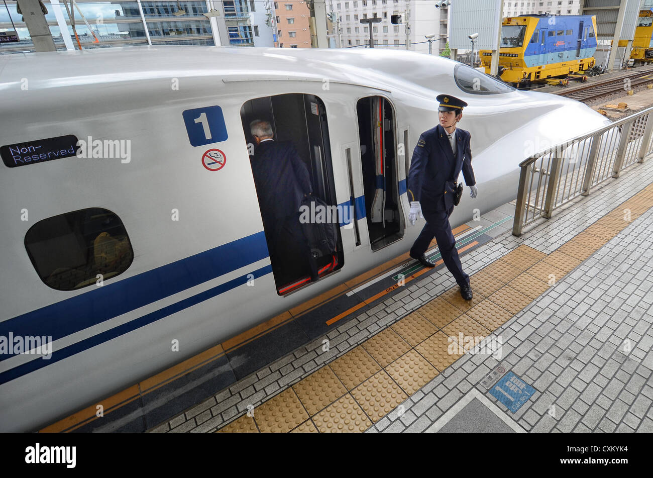 A train conductor steps off a Japanese bullet train as a passenger ...