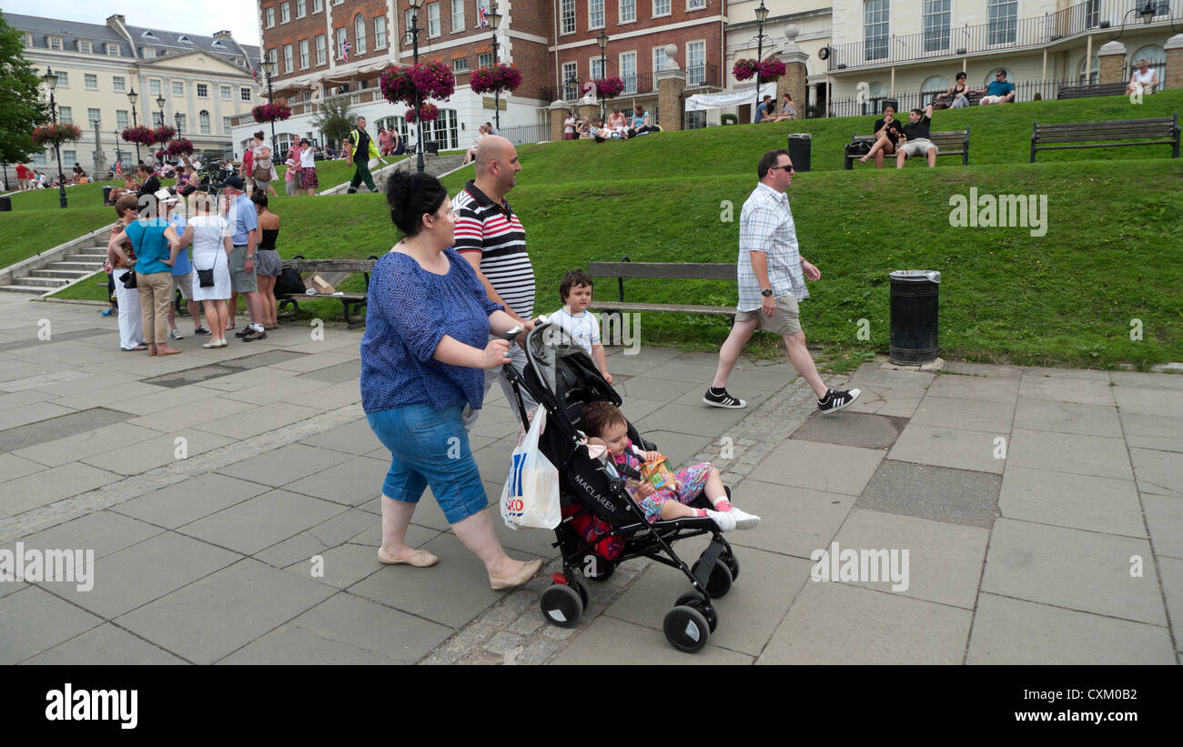A family with children strolling along the riverside path pushing a ...