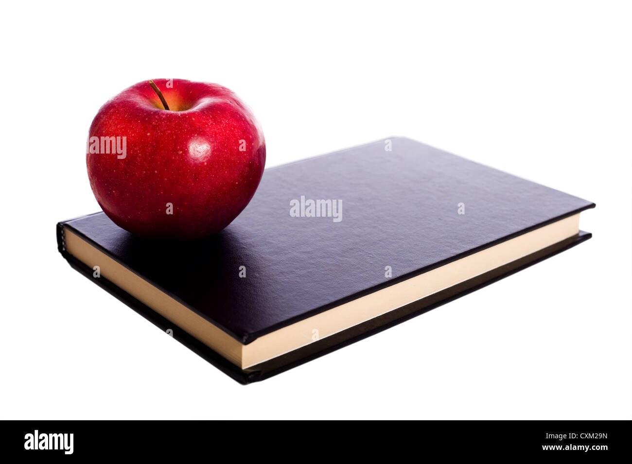A black school book and a red apple on a white background with copy ...