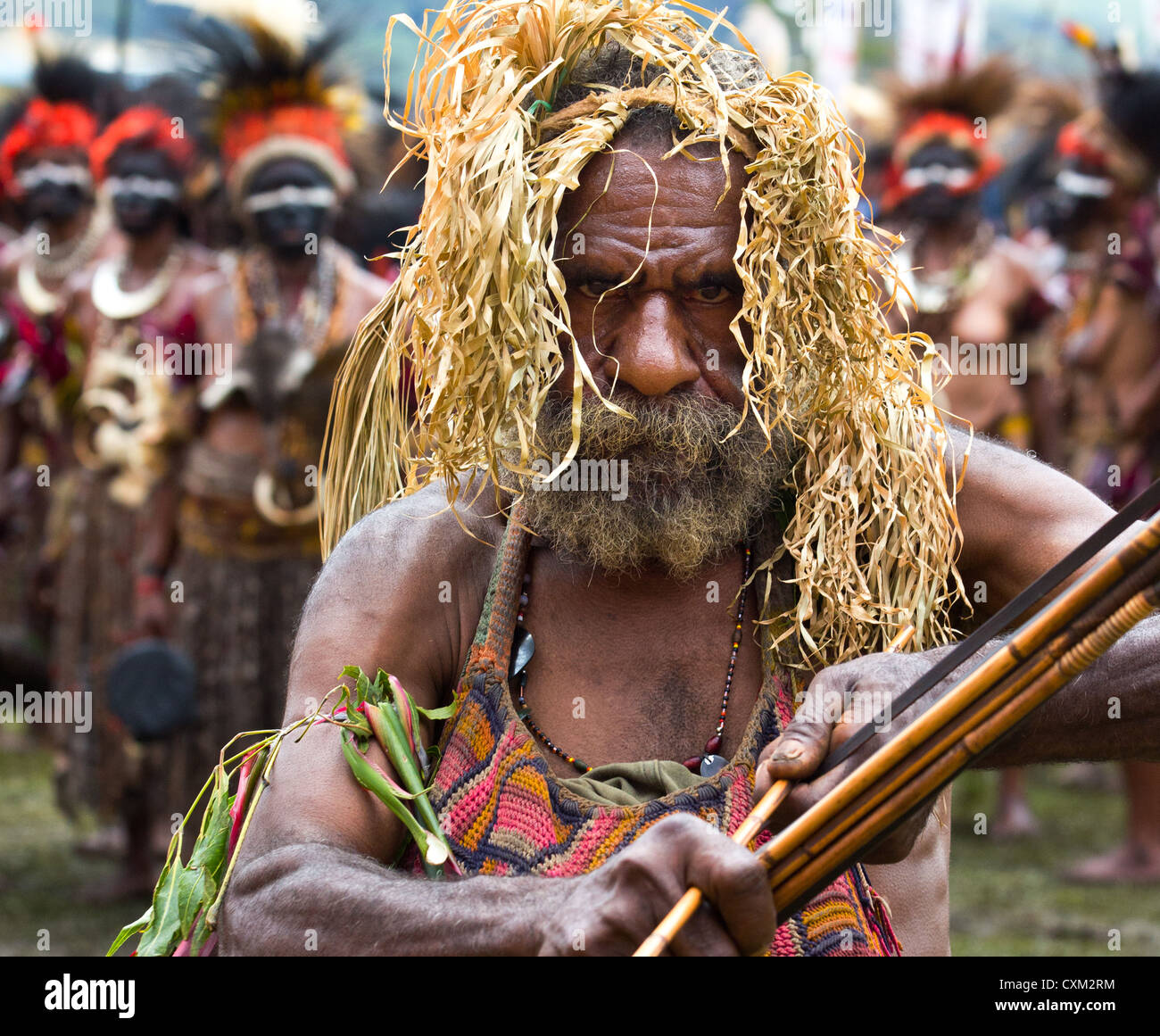 Old man wearing traditional tribal costume and pointing a bow and arrow ...
