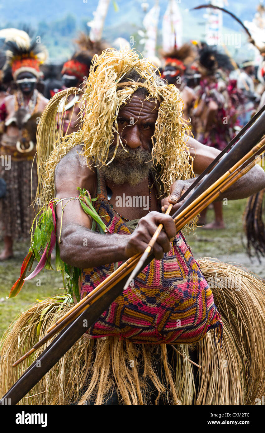 Old man wearing traditional tribal costume and pointing a bow and arrow ...