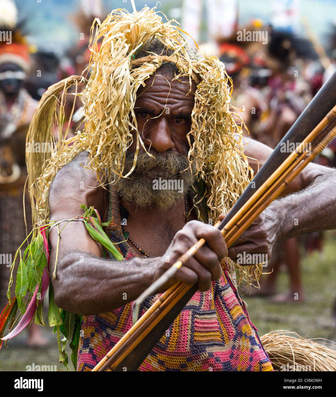 Old man wearing traditional tribal costume and pointing a bow and arrow ...