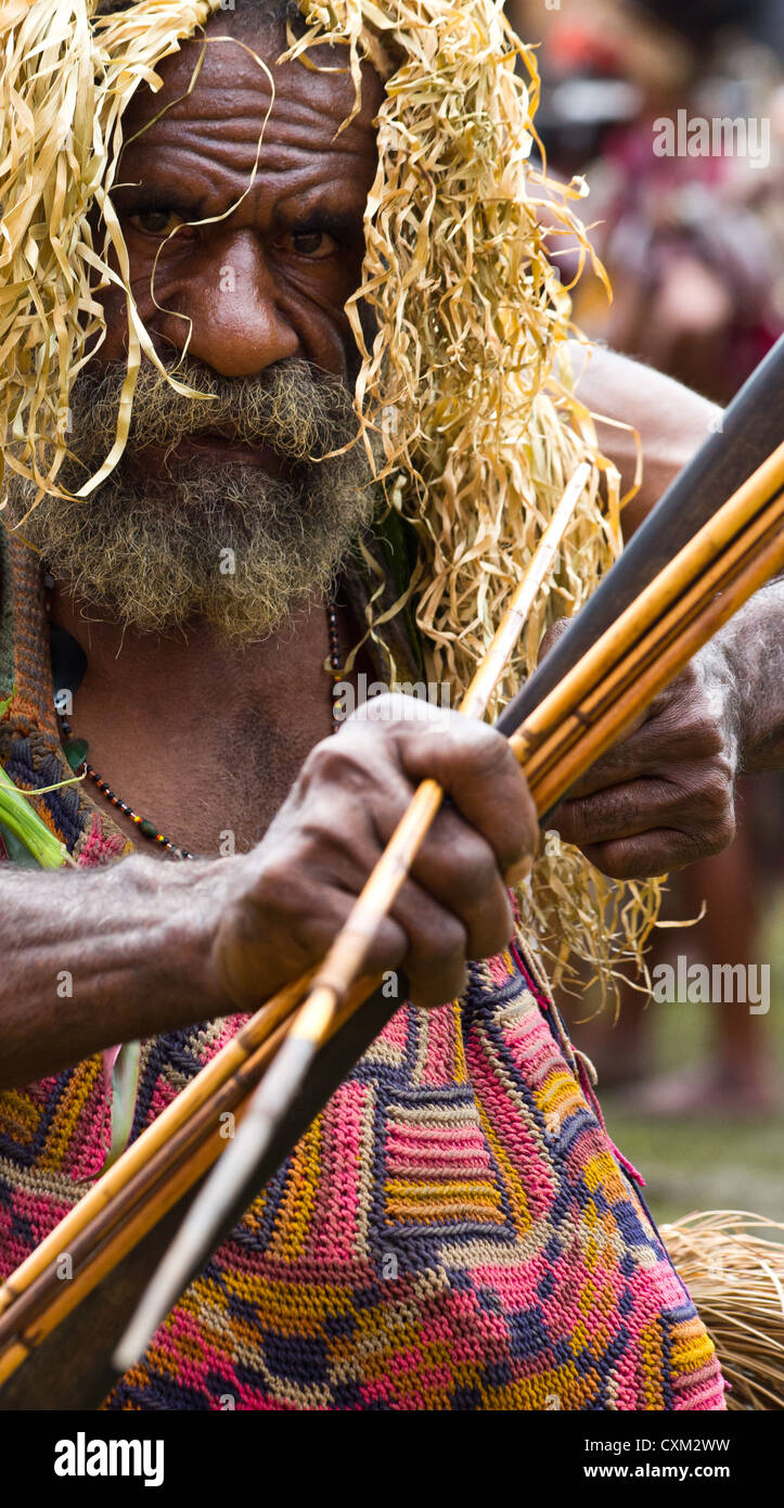 Old man wearing traditional tribal costume and pointing a bow and arrow ...